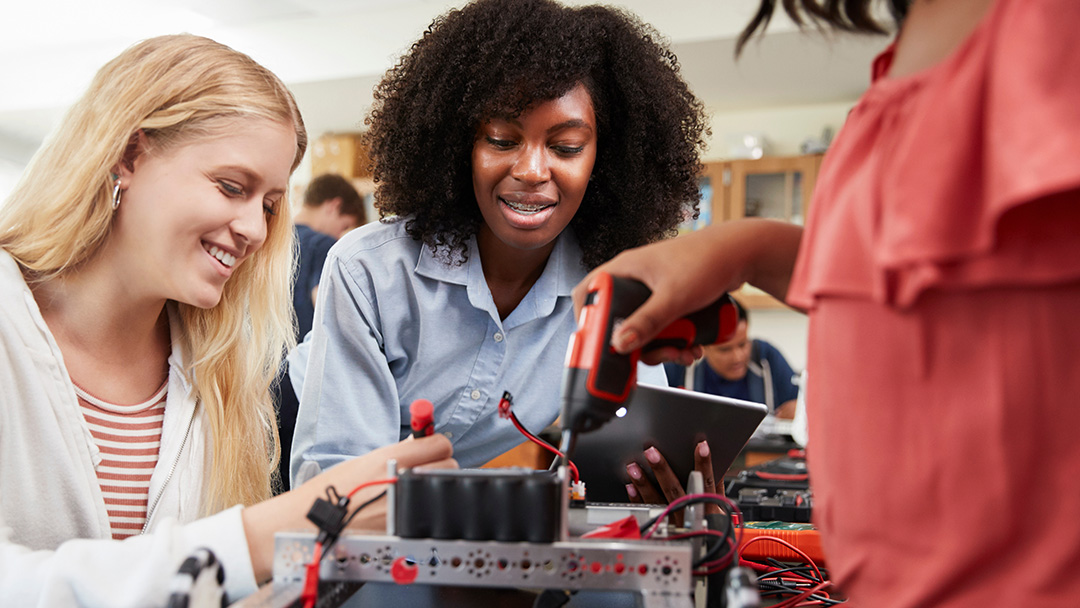 Teacher With Female Pupils Building Robotic Vehicle In Science Lesson - High-Tech High Heels